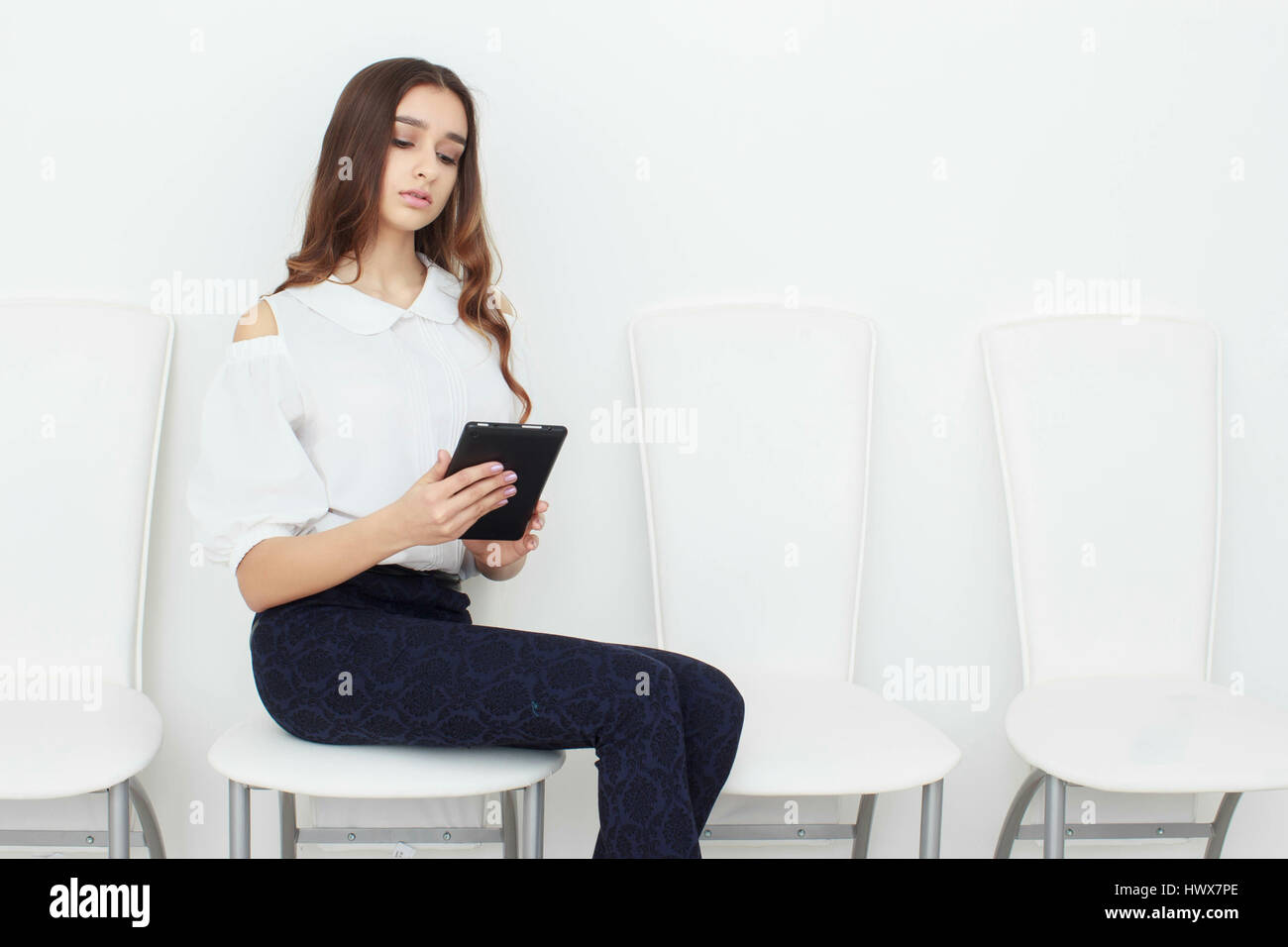 Jeune fille assise sur une chaise et à l'aide d'une tablette Photo Stock - Alamy