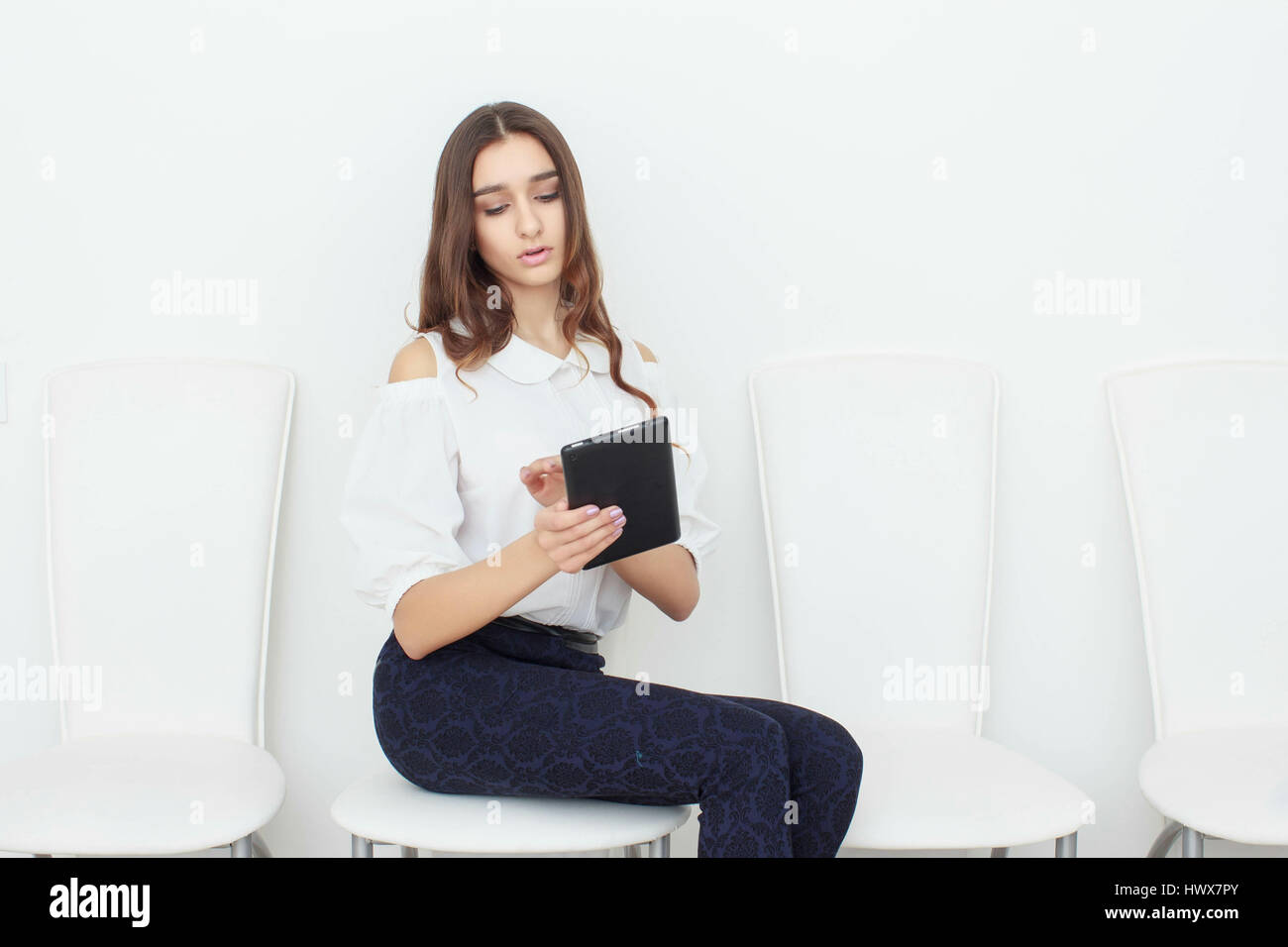 Jeune fille assise sur une chaise et à l'aide d'une tablette Photo Stock - Alamy