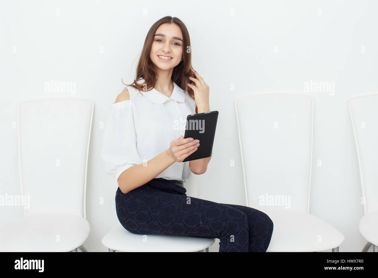 Jeune fille assise sur une chaise et à l'aide d'une tablette Photo Stock - Alamy
