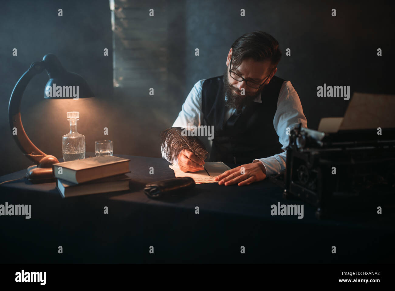 L'écrivain barbu dans les verres écrit avec une plume. Machine à écrire ...