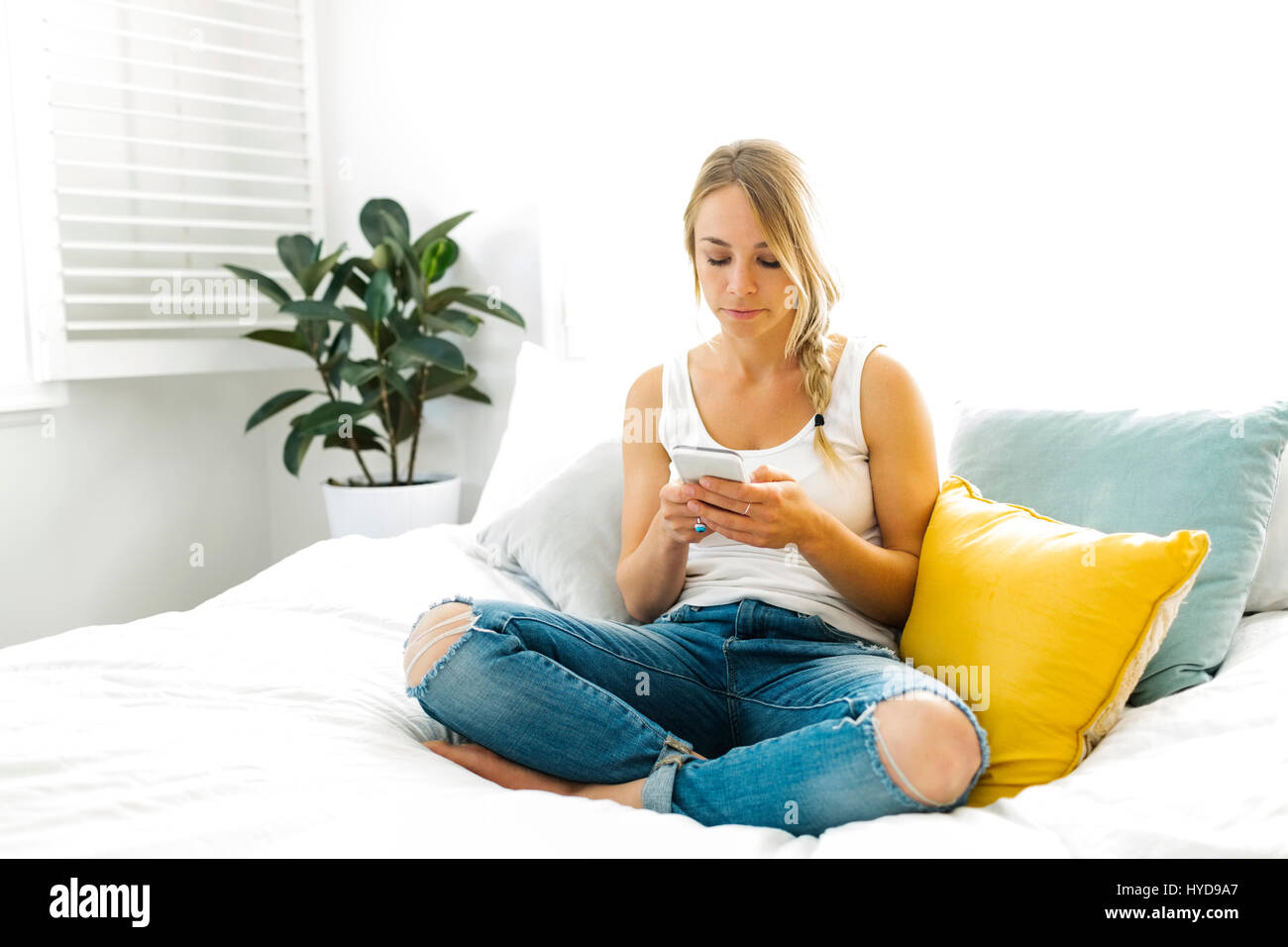 Jeune Femme Assise En Tailleur Sur Le Lit Banque De Photographies Et D