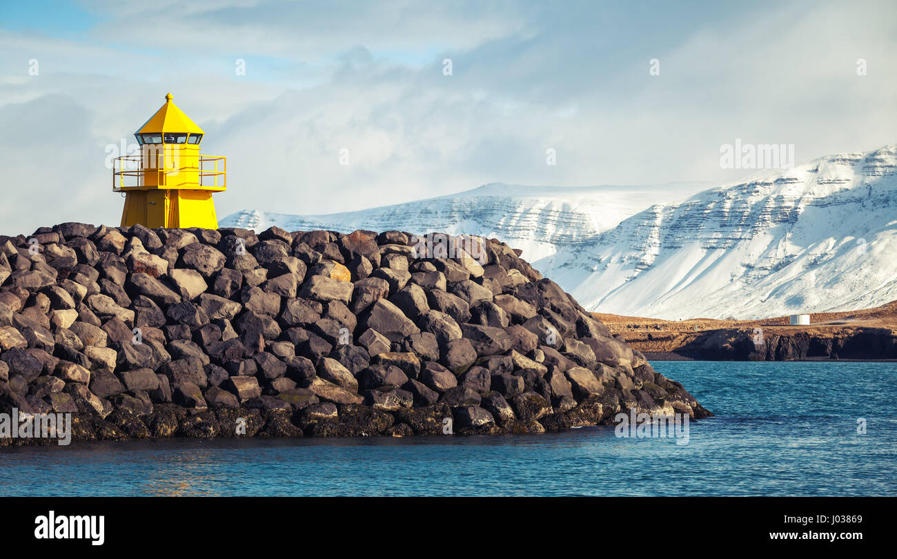 La tour phare jaune sur les brise-lames en pierre, l'entrée au port du ...