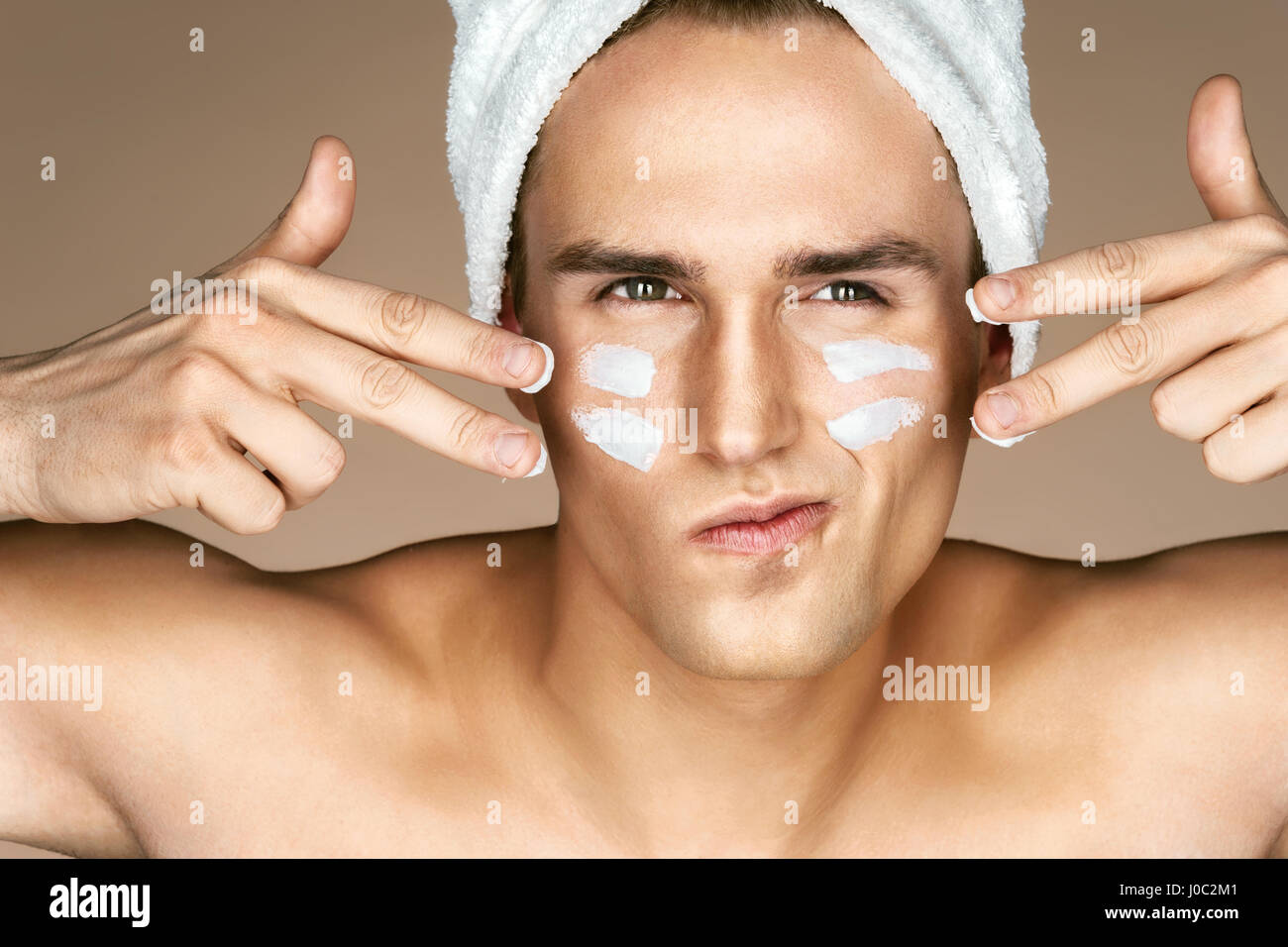 Jeune homme avec la crème hydratante sur le visage. Photo d'un homme ...