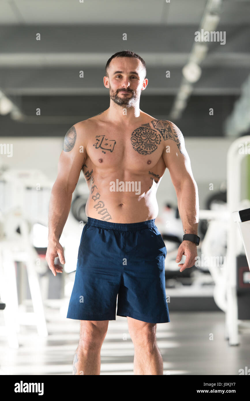 Portrait d'un jeune homme en bonne forme physique montrant son tatouage ...