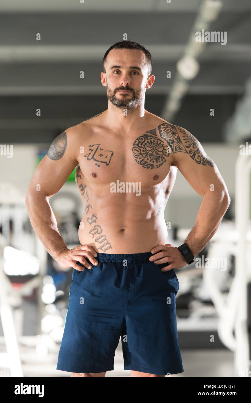 Portrait d'un jeune homme en bonne forme physique montrant son tatouage ...