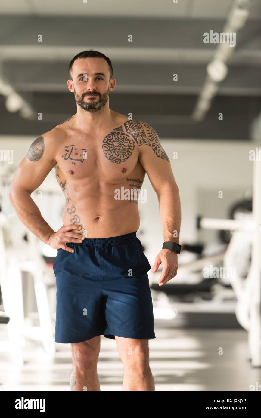 Portrait d'un jeune homme en bonne forme physique montrant son tatouage ...