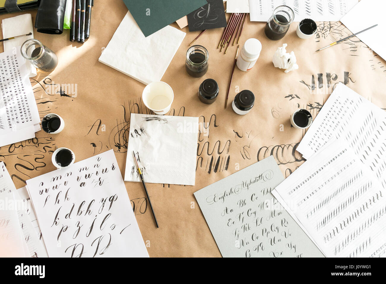 Feuilles de calligraphie, plumes, papier, encre et crayons sur un fond ...