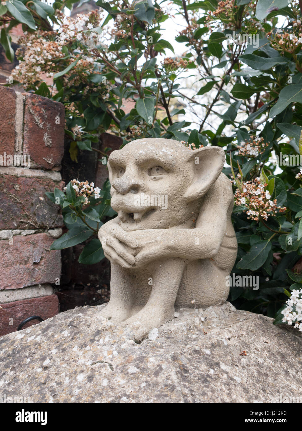 Un étrange gobelin gremlin statue en béton sur un pilier à l'extérieur ...