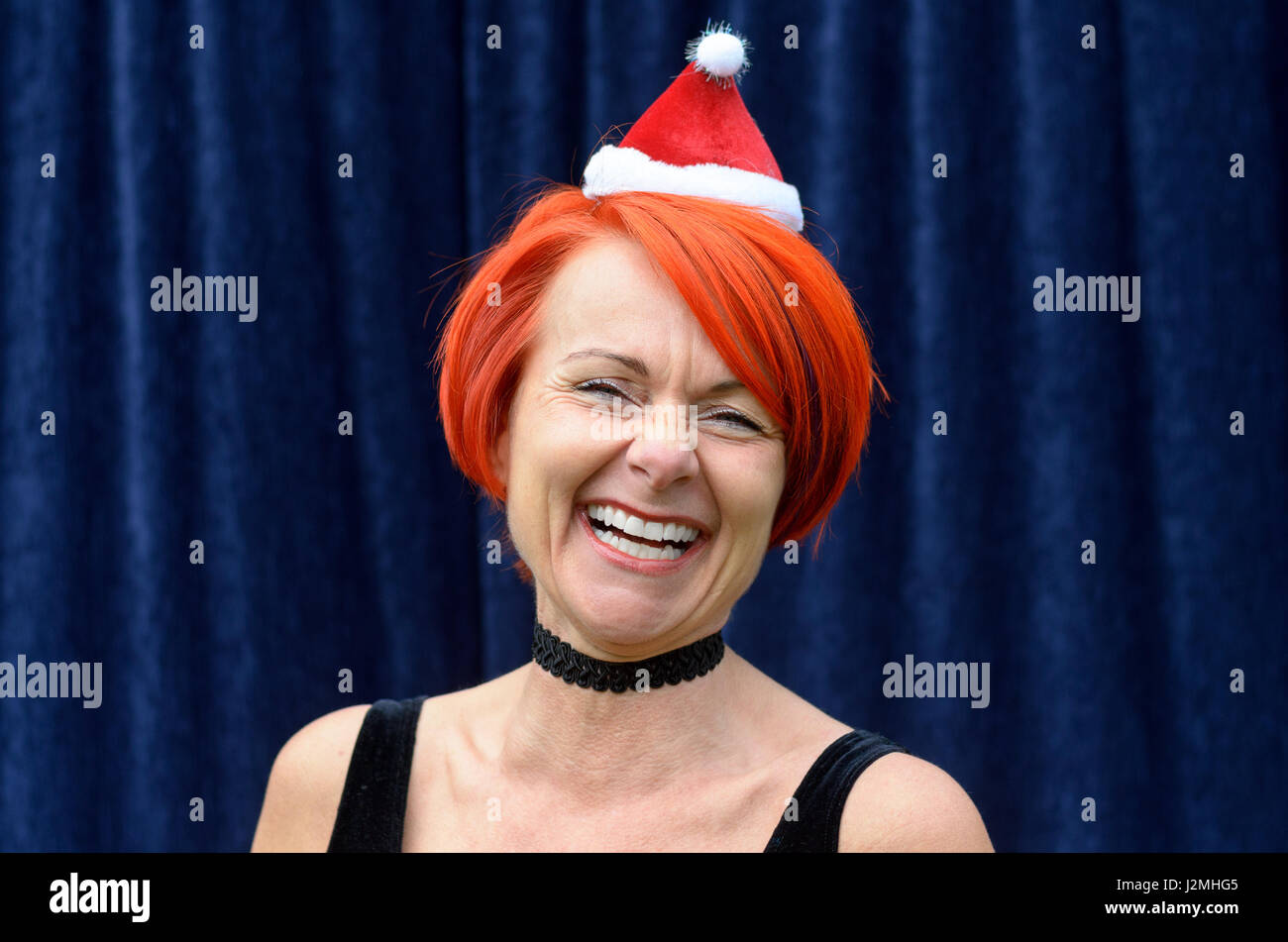 Vive la femme rousse riant dans un chapeau de Père Noël célébrer Noël ...