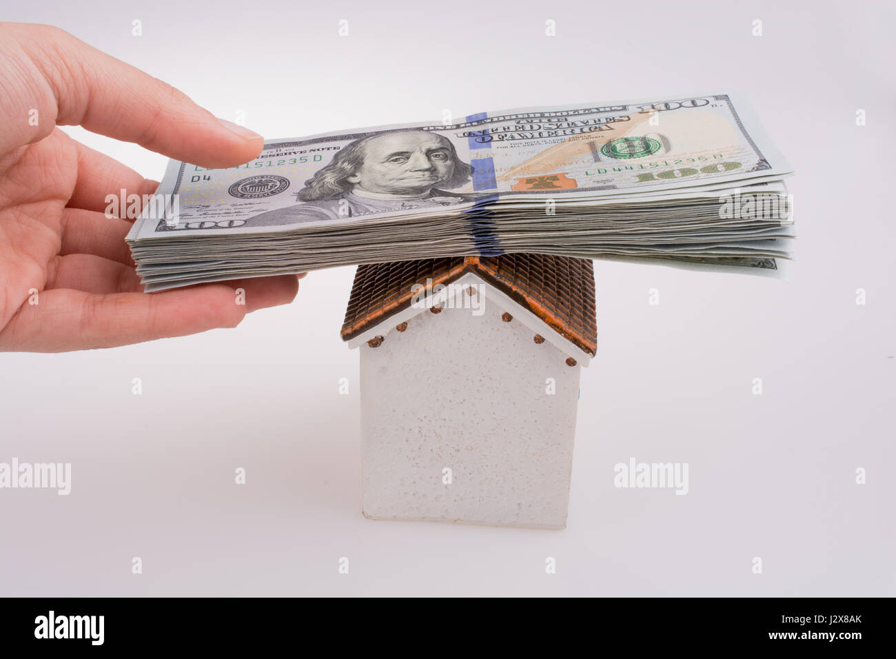 Hand holding American dollar billets sur le toit d'une maison modèle ...