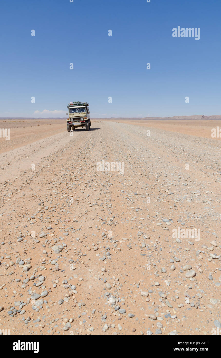 Land Cruiser 4x4 sur la route du désert rocailleux vide à l'Erg Chebbi ...