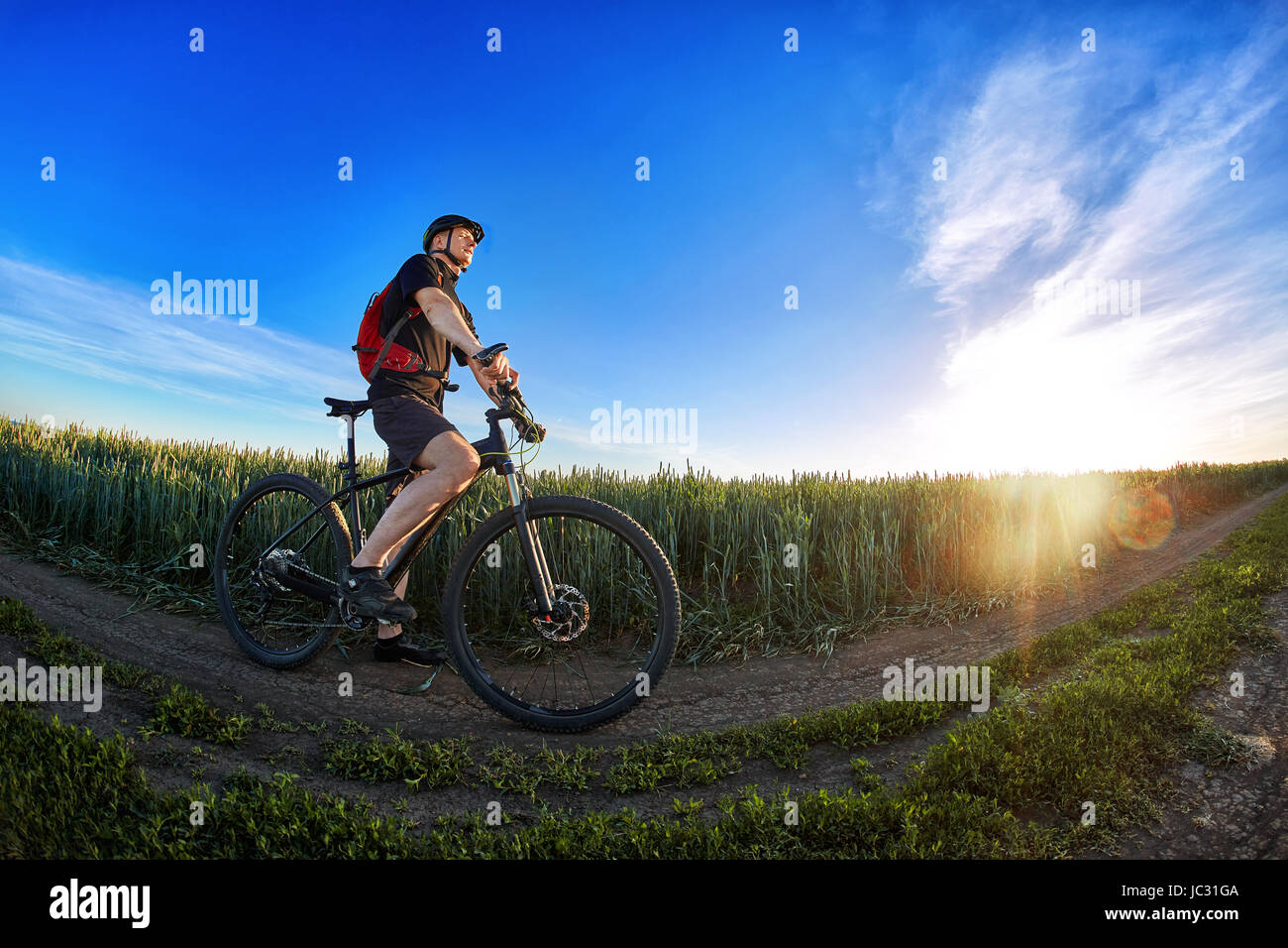 Grand angle de la cycliste debout sur le sentier sur le terrain contre ...