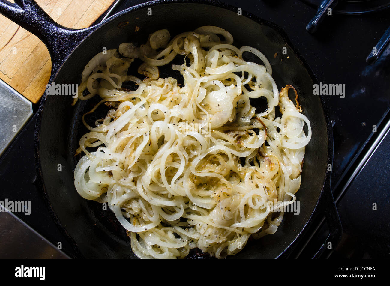 Carmaelizing les oignons dans la poêle en fonte sur la cuisinière Photo ...