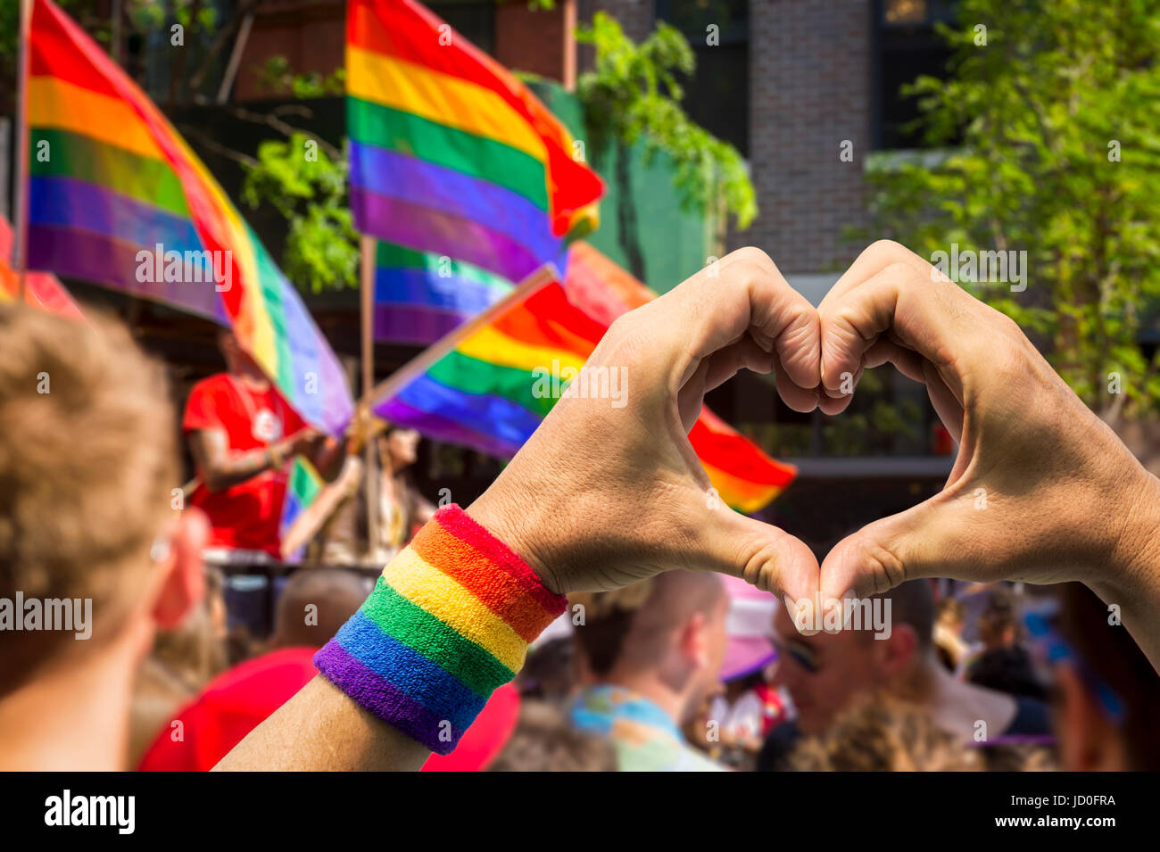 Des mains faire signer et vague en face d'un des drapeaux arc-en-ciel ...