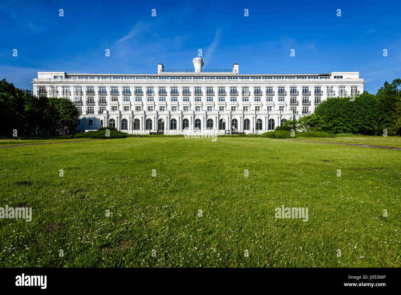 Parc verdoyant avec des caillebotis et grand bâtiment de l'hôtel blanc ...