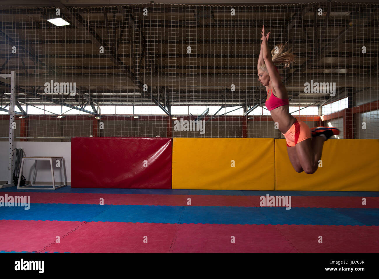 Athlète féminin effectuant un saut dans la salle de sport - l'un des ...