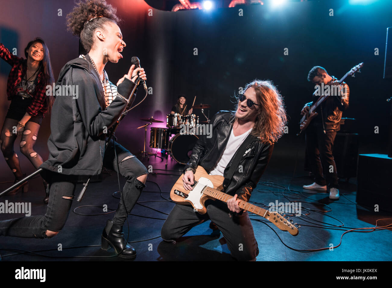 Chanteuse avec microphone et rock and roll groupe jouant de la musique ... Chanteuse avec microphone et rock and roll groupe jouant de la musique ...