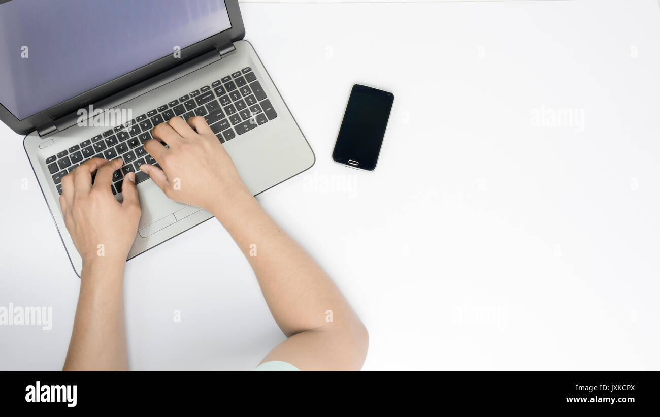 Les mains d'un ordinateur portable avec un mobile mis de côté, sur un ...