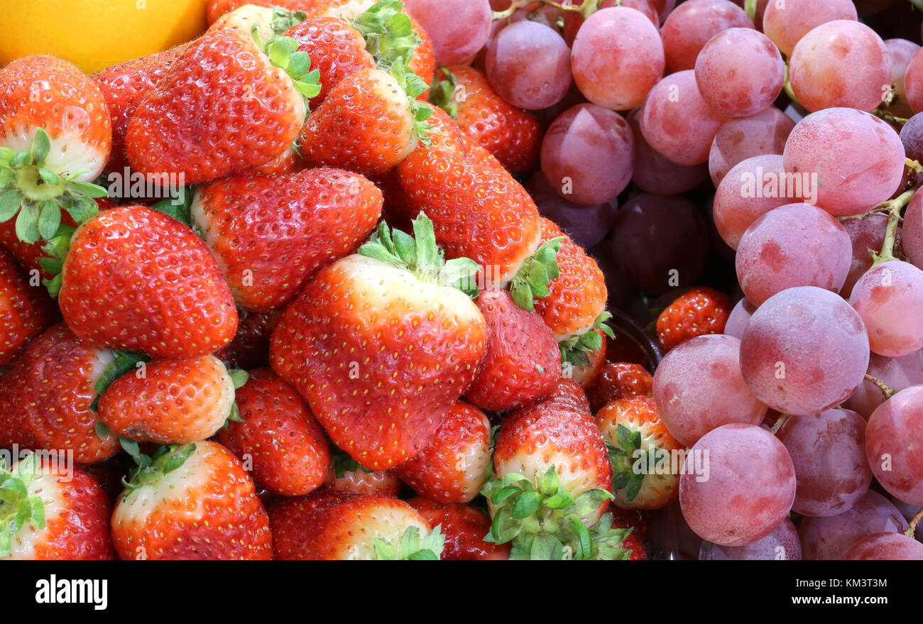 Arrière-plan de big red fraise mûre et grappes de raisin deux prémices ...
