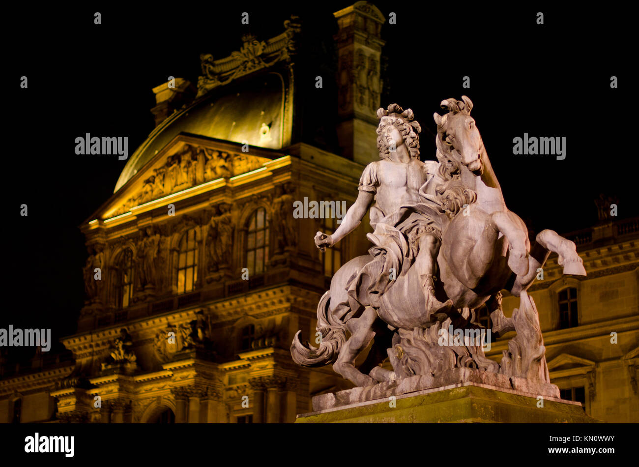 Paris, France. Palais du Louvre de nuit. Statue ; le roi Louis XIV à ...