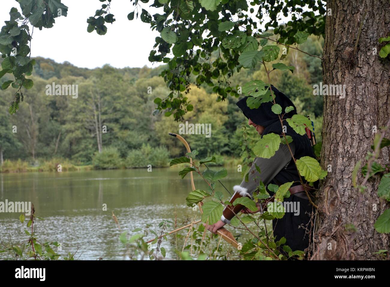 archer médiéval avec capot noir se cache derrière l'arbre au bord du ...