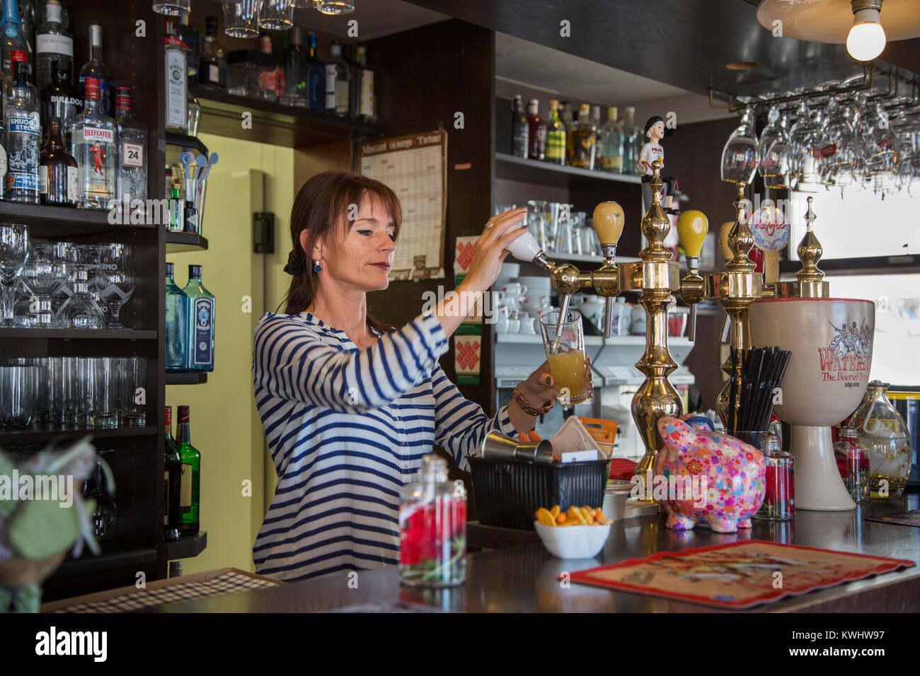 Barmaid dimensions une pinte de bière belge dans le verre dans le café ...
