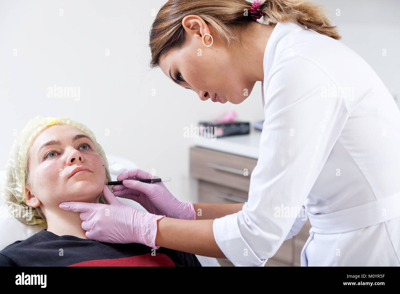 Jeune femme médecin esthéticienne au sarrau blanc et gants stériles ...
