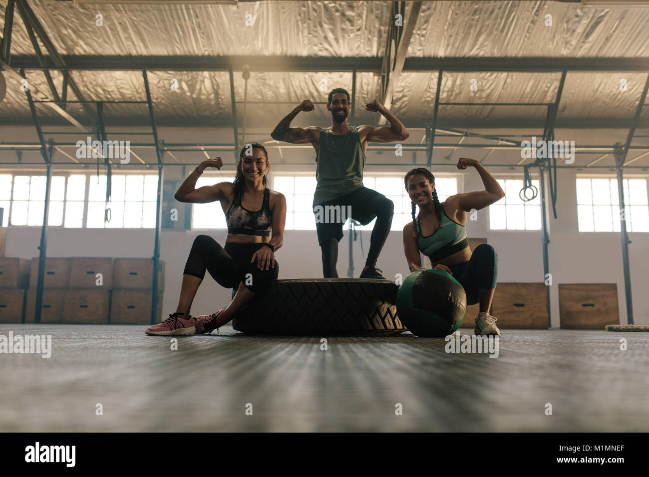 Les jeunes gens qui posent leurs muscles et de flexion dans une salle ...