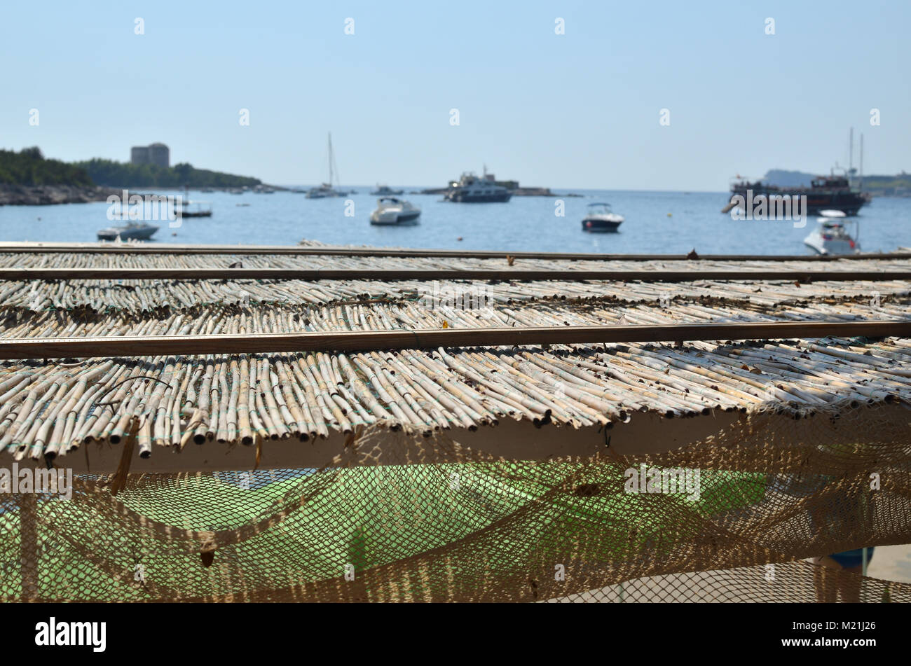 Toit de paille sur une plage, et différents bateaux et navires sur une ...