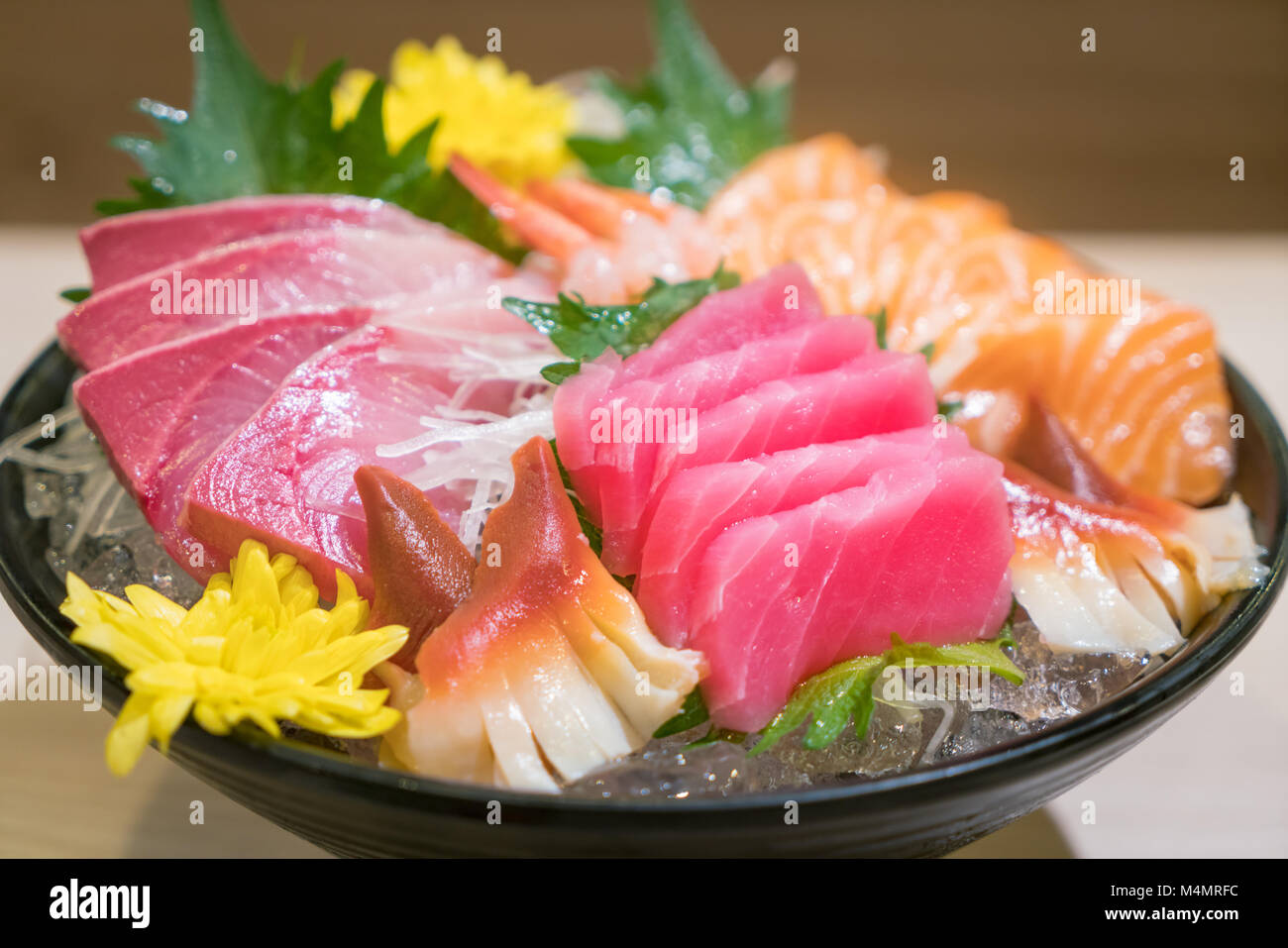 Tranches de sashimi mixte de poissons sur la glace en noir bol. Sashimi ...