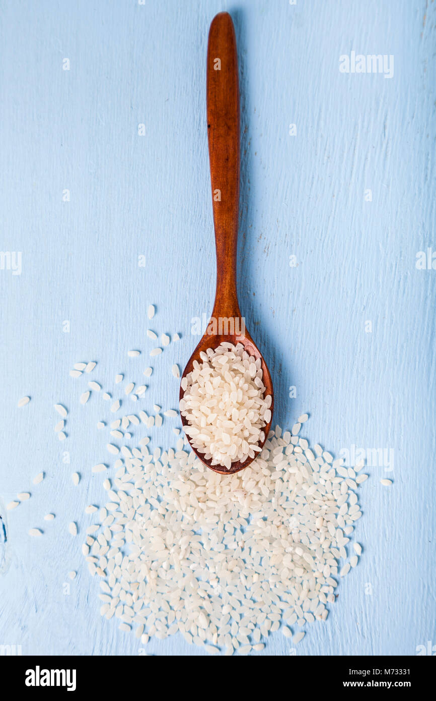 Et la cuillère de riz cru sur un fond en bois bleu, vue du dessus ...