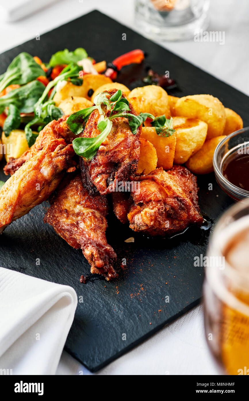 Ailes de poulet rôti avec des pommes de terre frites Photo Stock - Alamy