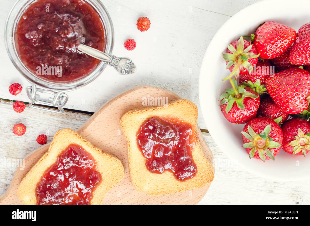 Toasts avec de la confiture de fraise pour le petit déjeuner le rusric blanc fond de bois. Vue d ...