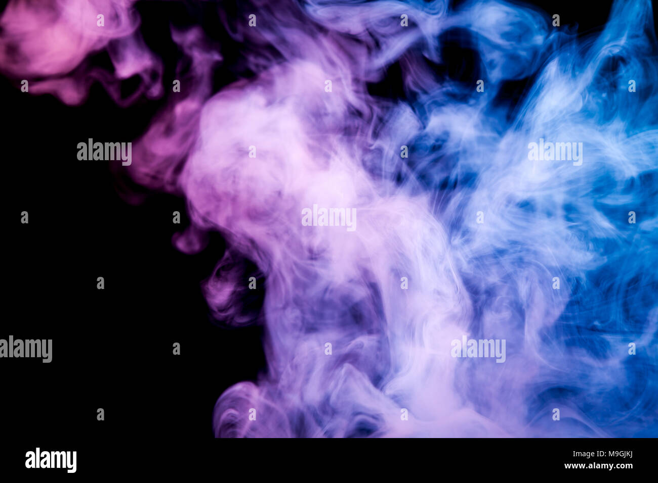 La fumée épaisse de couleur bleu et violet sur un fond noir isolé ...