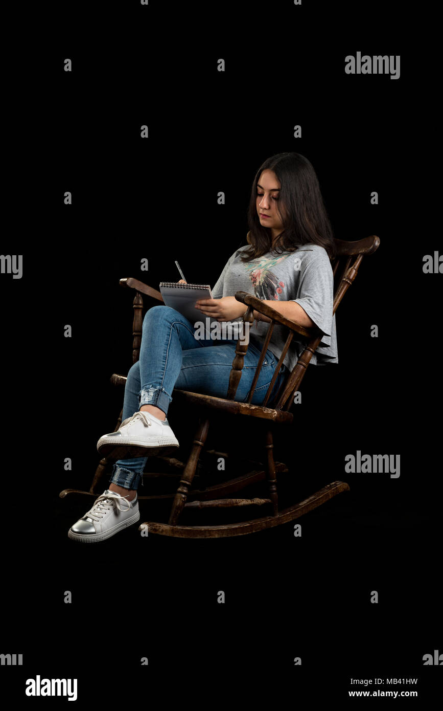 Teenage girl écrire ou dessiner avec un crayon dans un rocking-chair ...