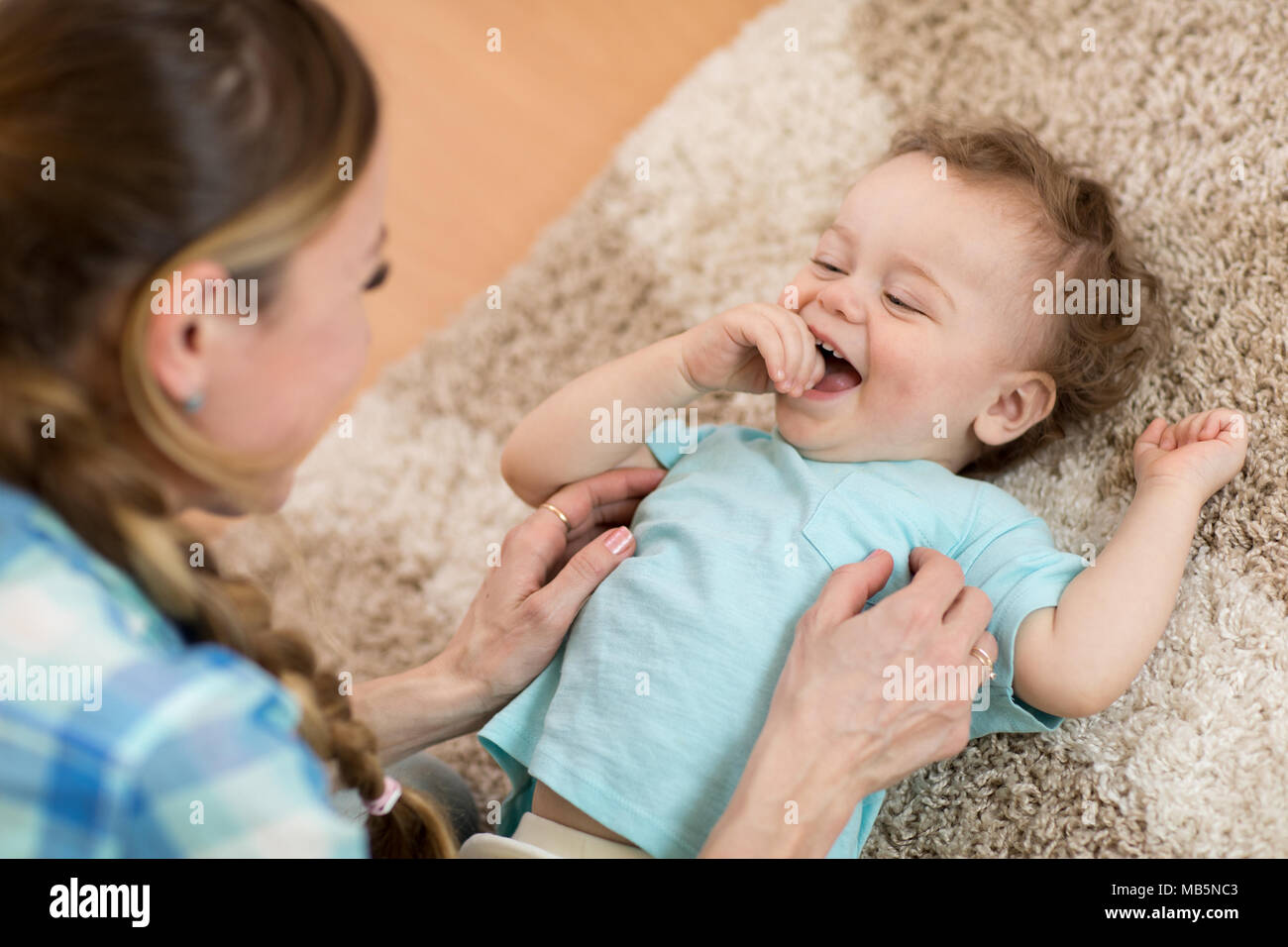 Mère de chatouiller son petit enfant sur un tapis à la maison Photo ...