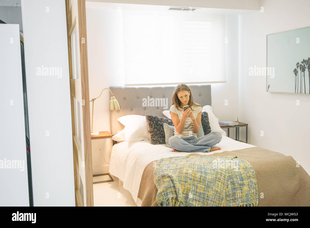 Jeune Femme Assise En Tailleur Sur Le Lit Banque De Photographies Et D