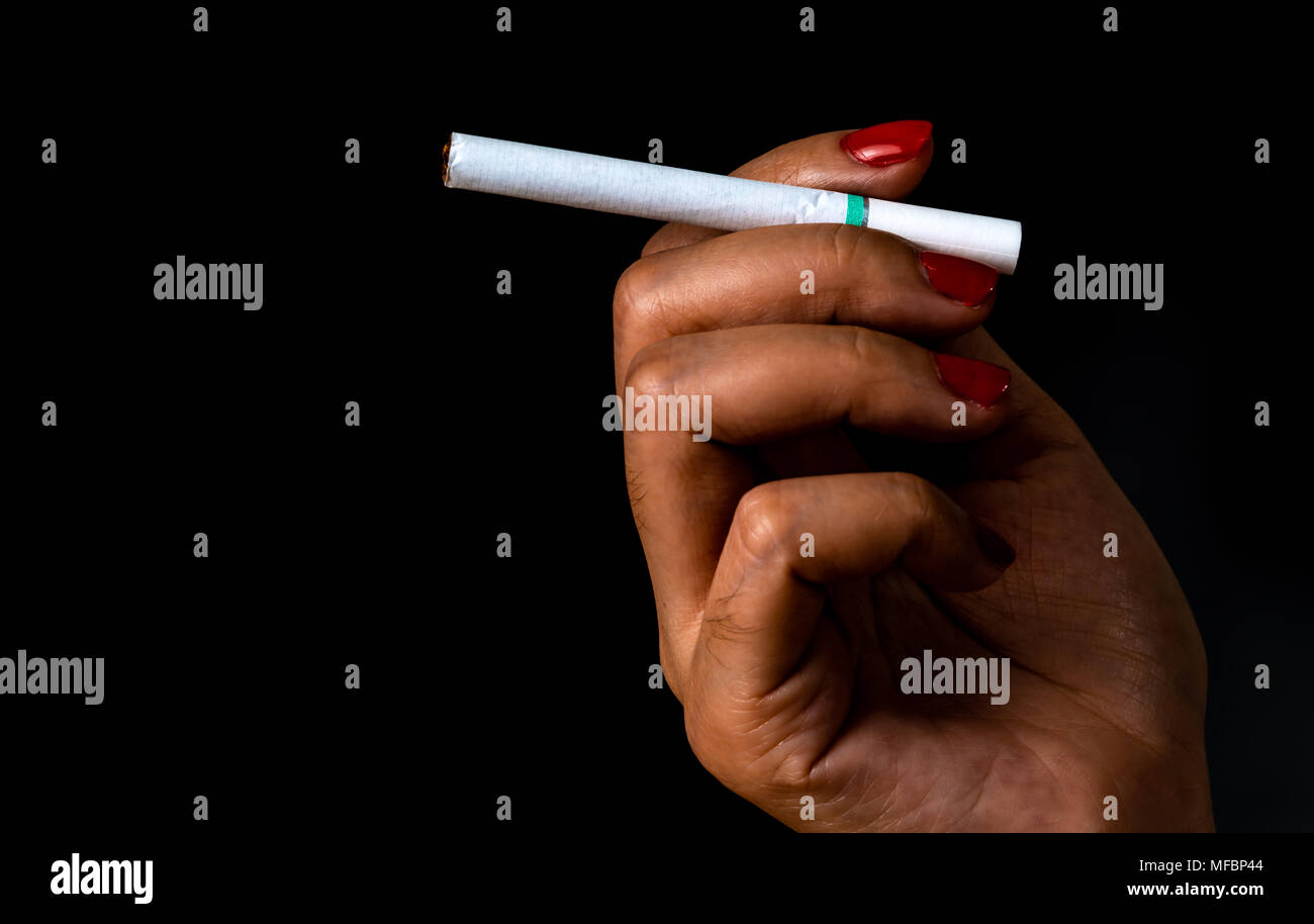 Cigarette à la main Femme avec clou rouge isolé sur fond noir. Le ...