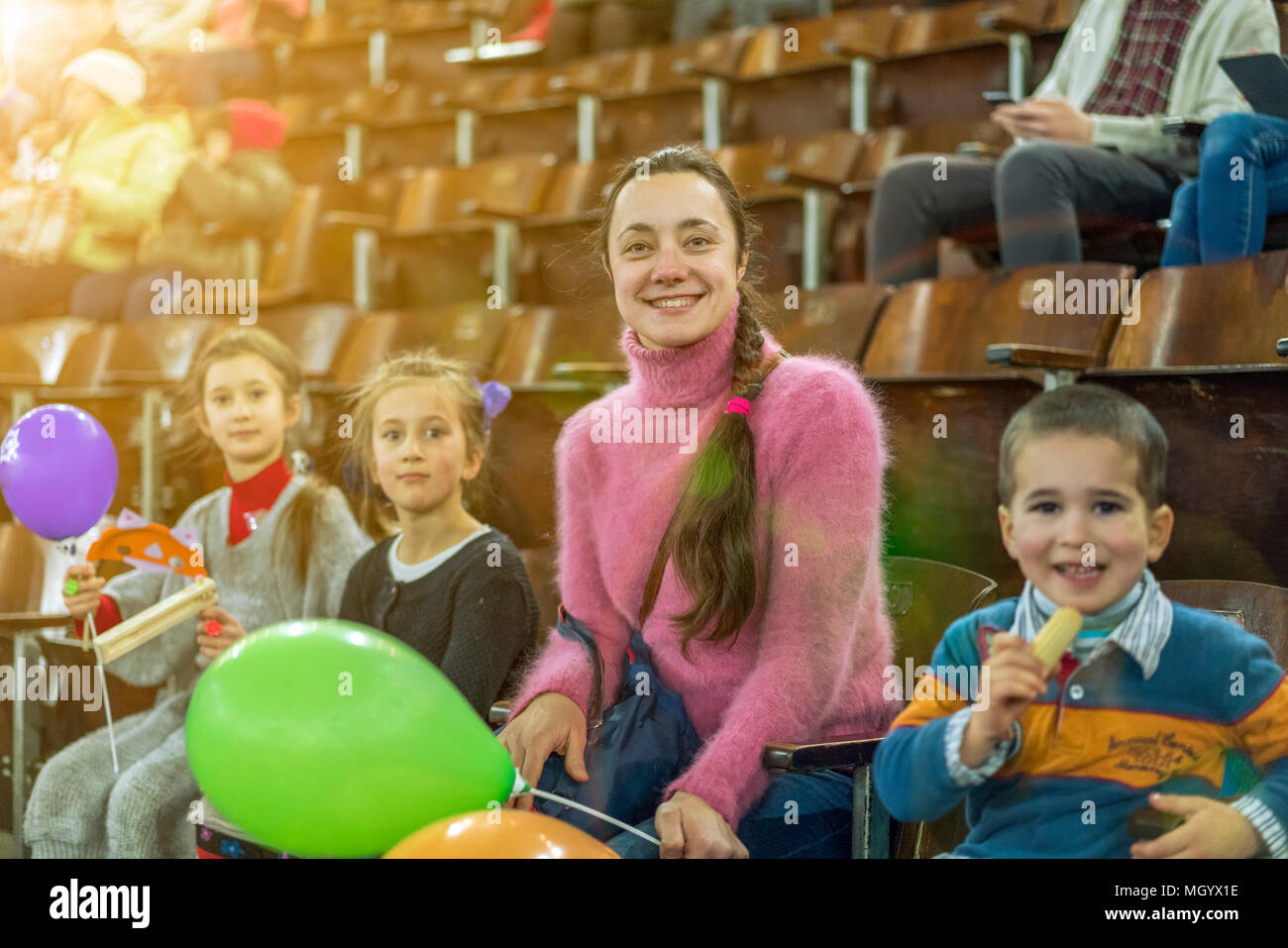 Une mère de trois enfants, est assis à un concert. Les enfants avec des ...