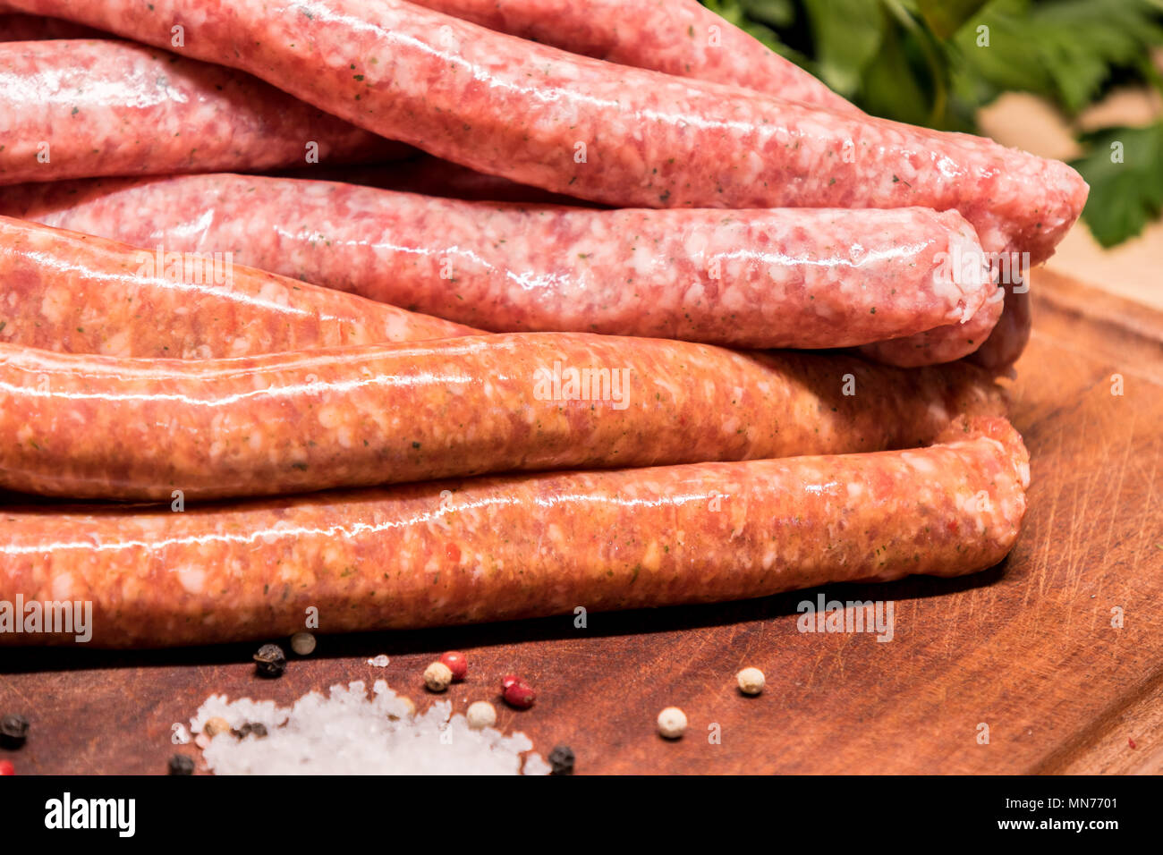 Les saucisses crues avec du chili et des herbes sur une planche en bois avec des épices Photo ...