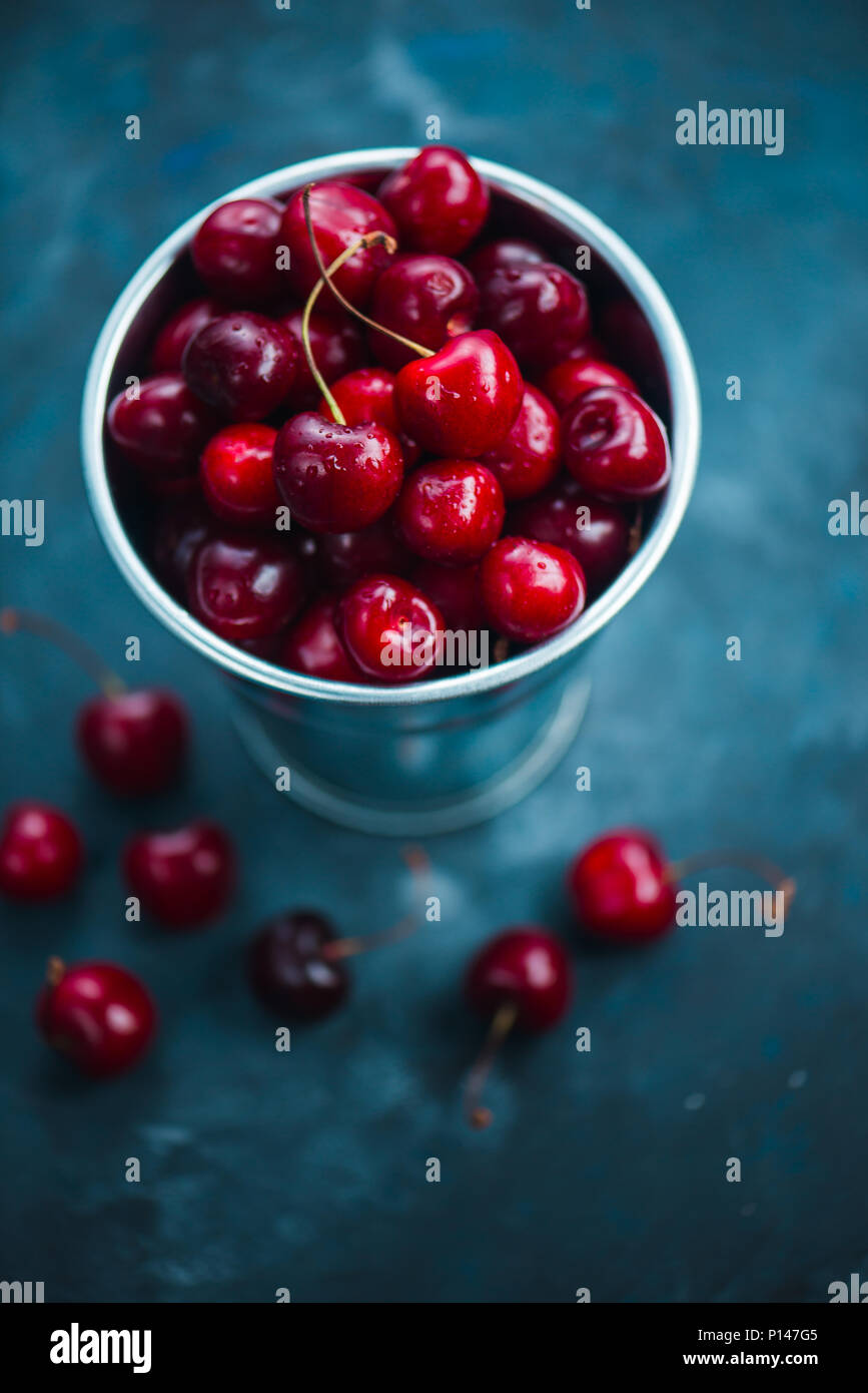 Cerises avec un petit seau en métal sur une base de béton gris, l'été ...