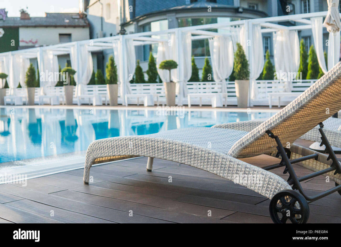 Chaise longue près de la piscine avec de l'eau propre en journée ...