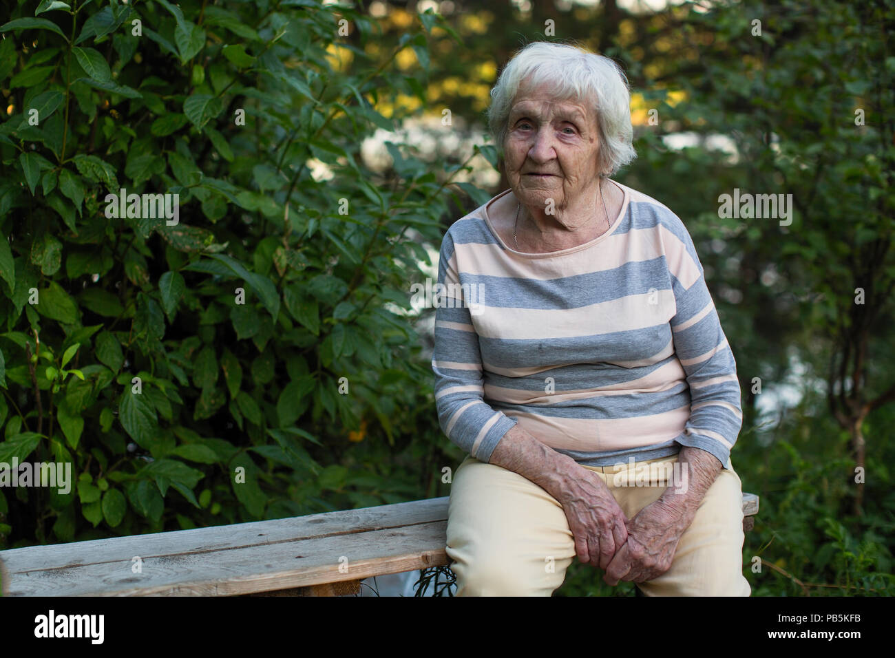 Vieille Dame Assise Sur Un Banc En Bois Banque De Photographies Et D