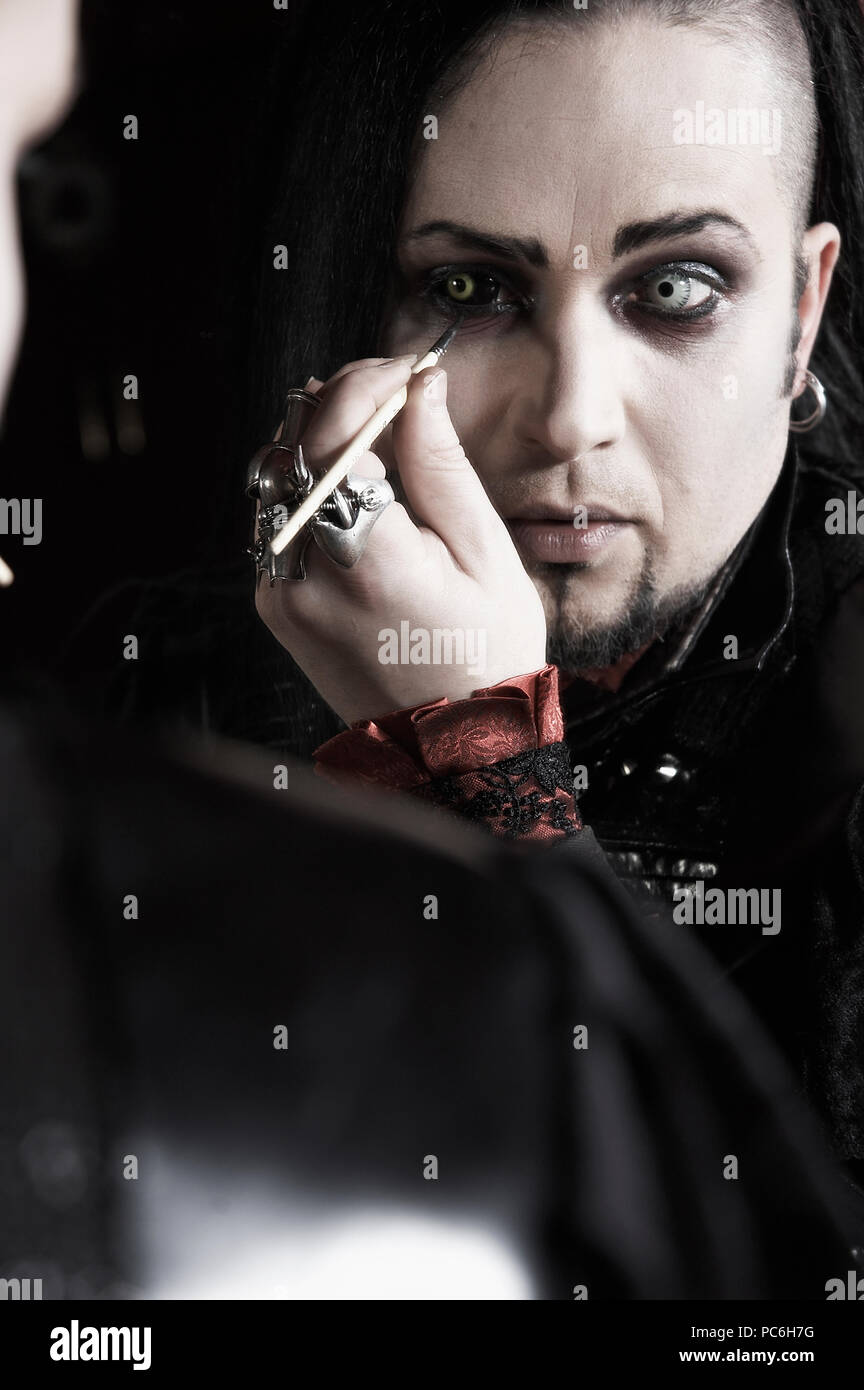 Un homme gothique applique son maquillage dans le miroir Photo Stock ...