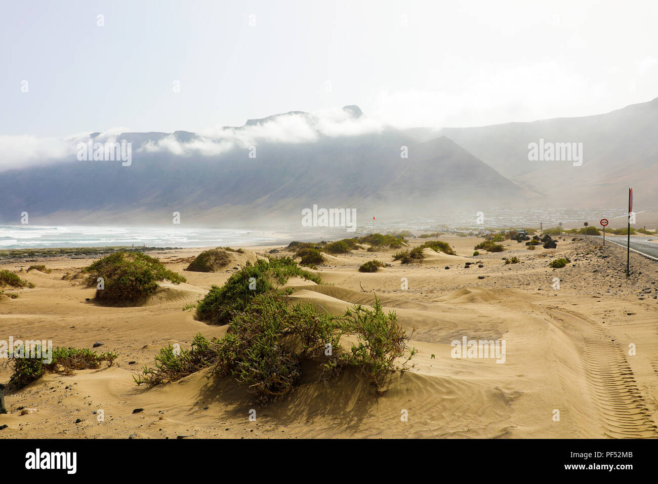 Caleta de Famara avec paysage désert de dunes et de la brume sur les ...