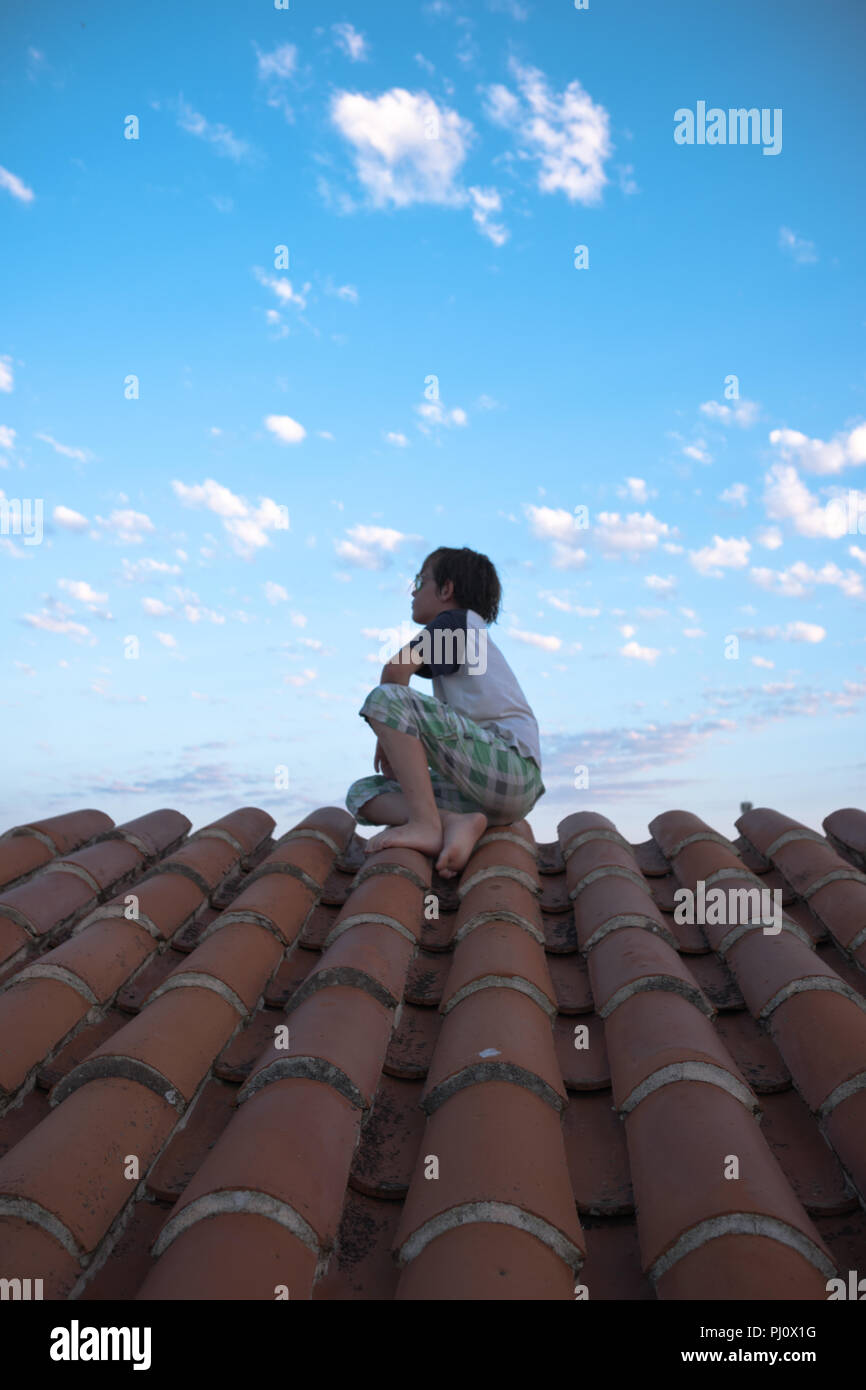 Garçon de 11 ans se trouve perché sur un toit de tuiles de villa à ...