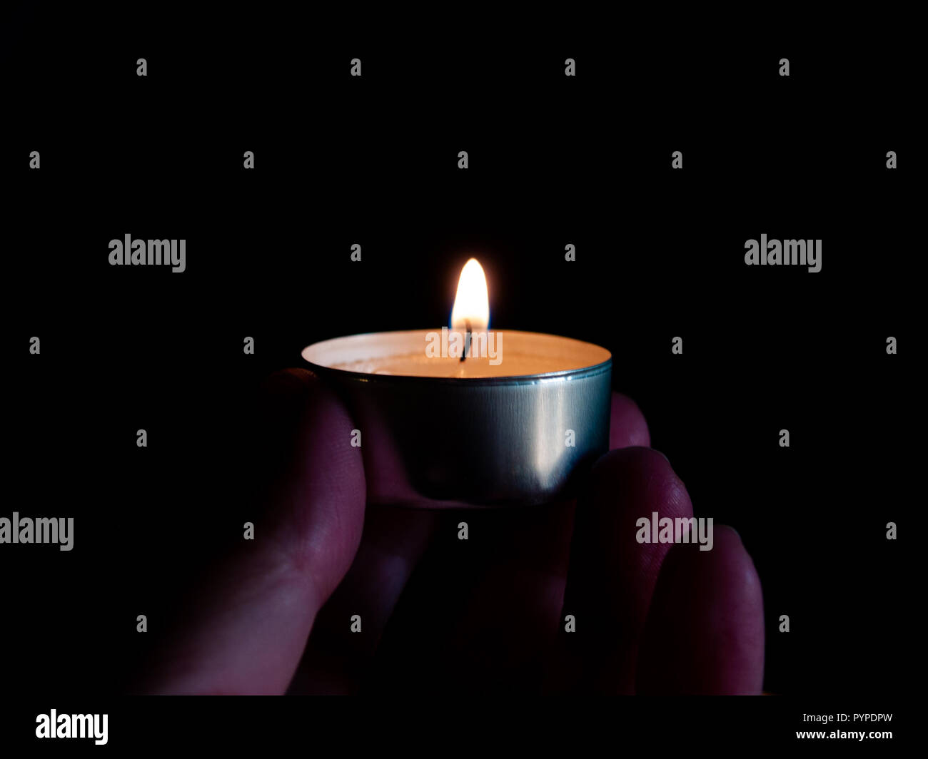 Une personne avec un cierge allumé avec une flamme orange dans la main ...