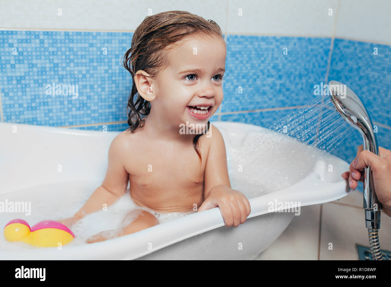 Belle petite fille prendre un bain à la maison. Un mignon bébé est ...