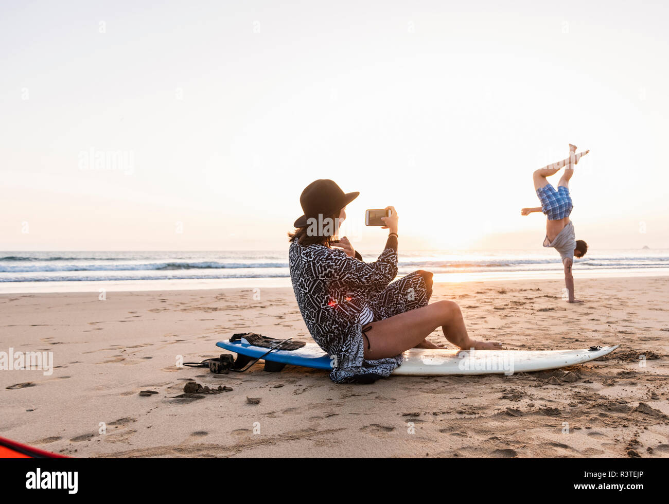 Jeune femme assise sur une planche de surf, la prise de photos de jeune ...