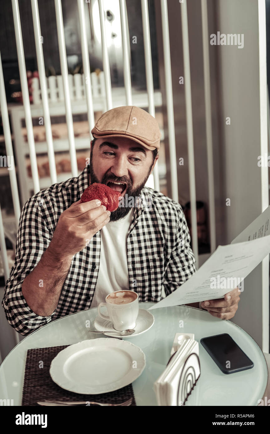 Carte des desserts. Bien à l'homme tenant un menu tout en mangeant de ...